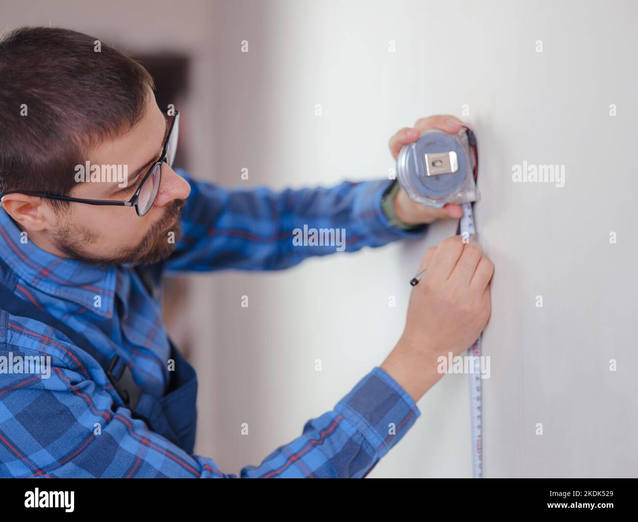 young man in blue work suit holding measure tape isolated on white ...