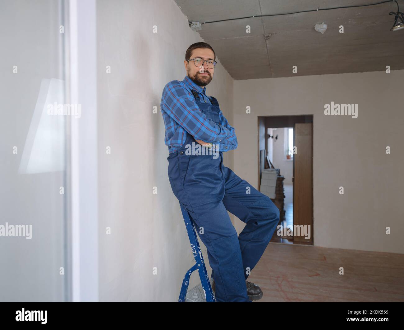 young man in blue work suit doing Repair apartment. Home renovation ...