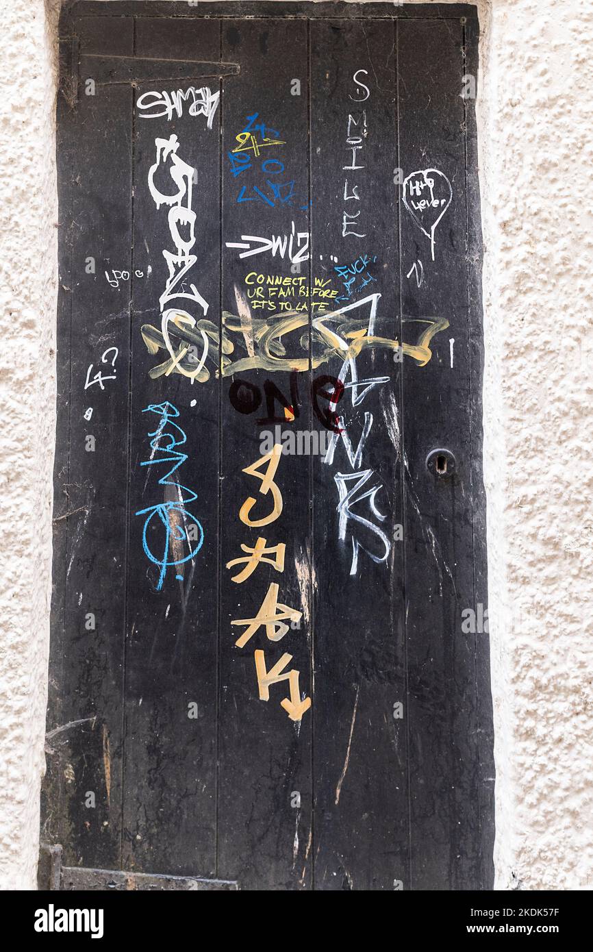 Ugly graffiti scrawled over a small wooden door. In Cornwall in the UK ...