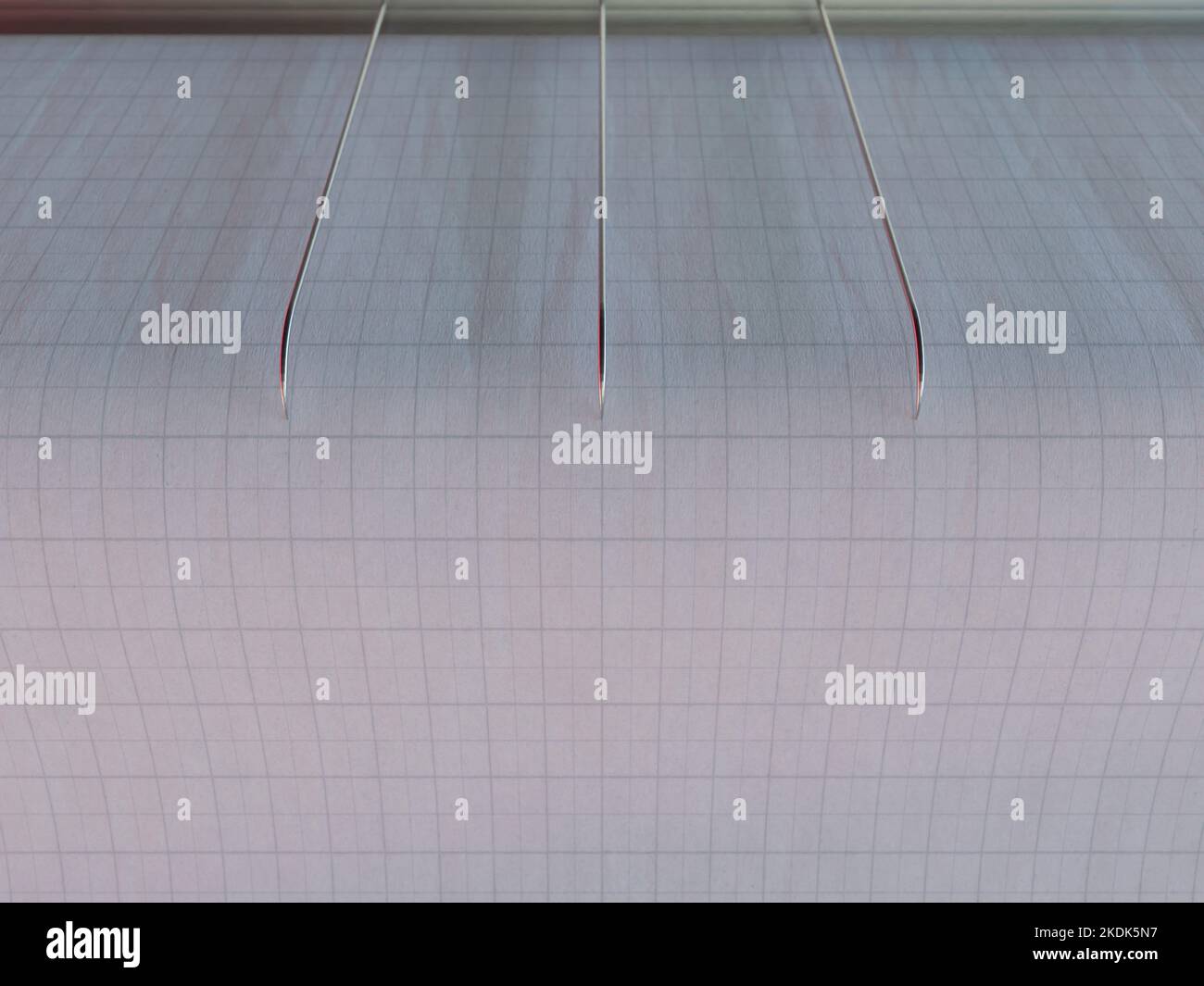 A closeup of seismograph machine needles on graph paper depicting ...