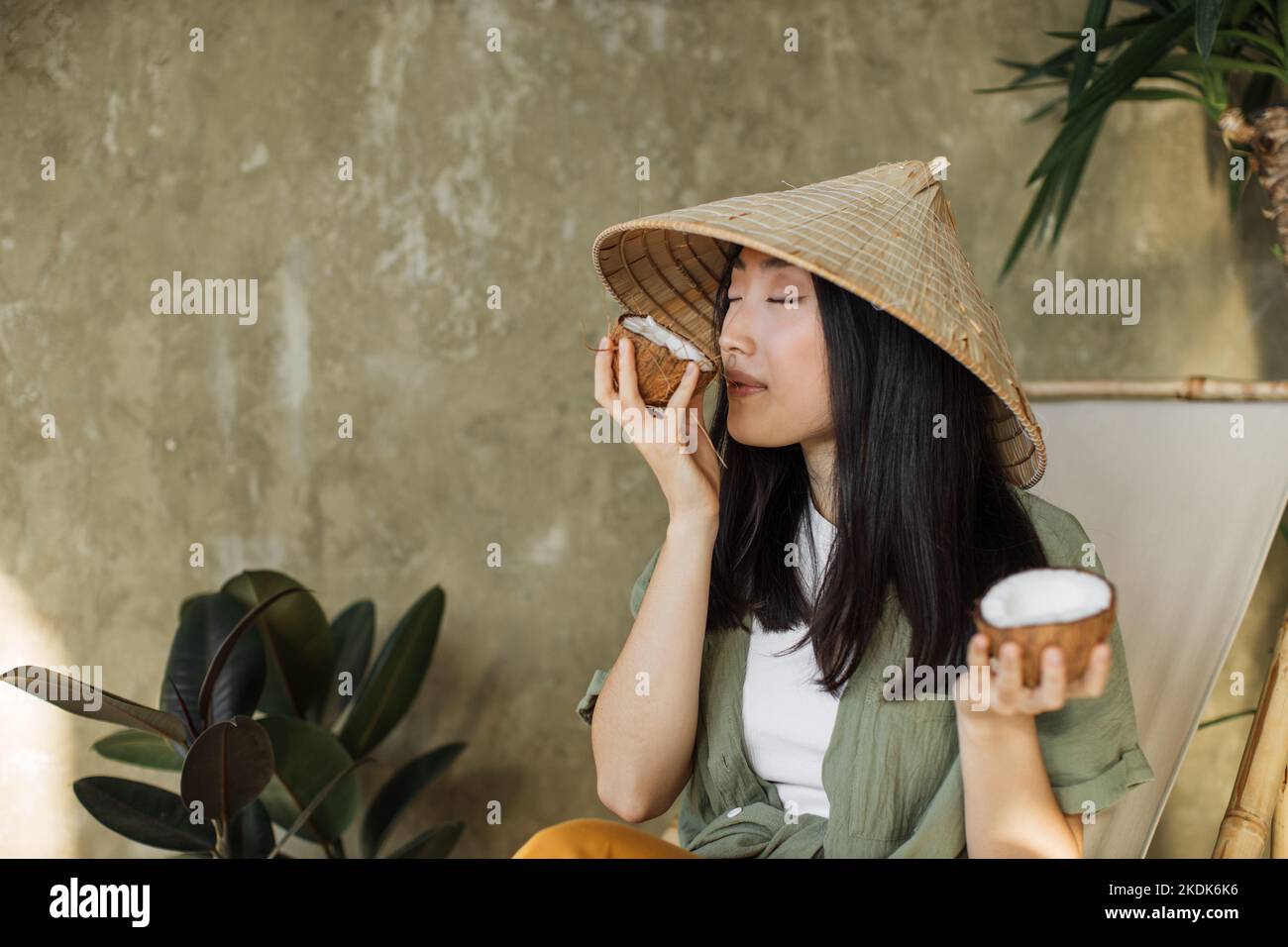 Attractive asian woman in traditional conical hat enjoying smell of ...