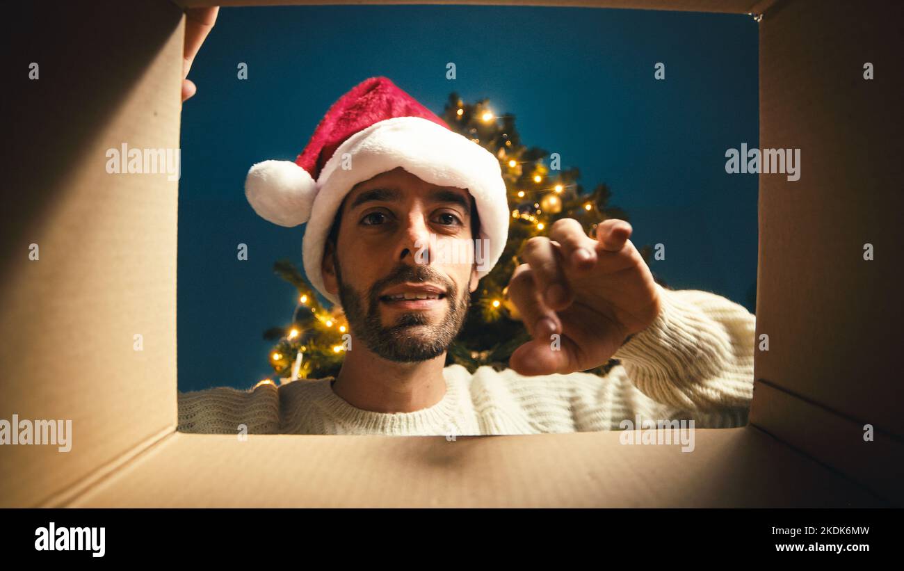 Happy guy opens and looks inside a Christmas box Stock Photo - Alamy
