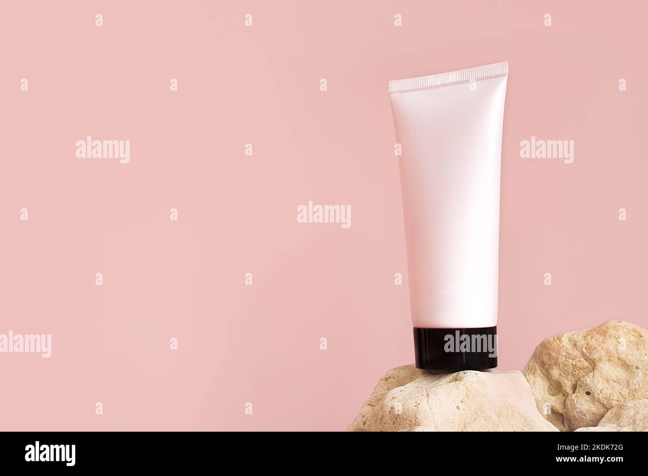 Unbranded pink squeeze bottle cream tube with black screw cap on stone ...