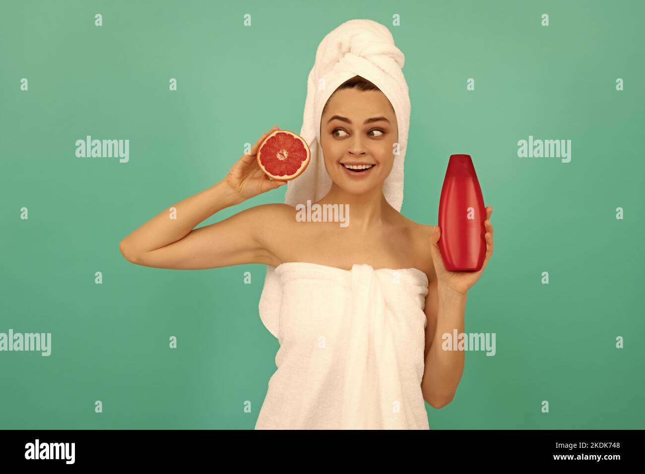amazed lady in towel with grapefruit shampoo bottle on blue background ...