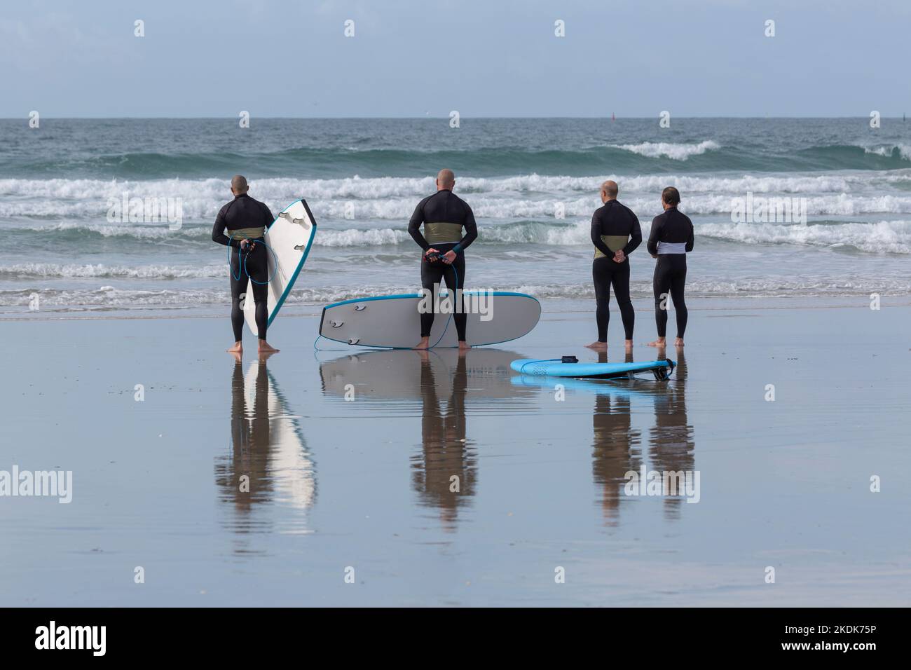 A group of surfers with blue apprentice surfboards and black wetsuits ...