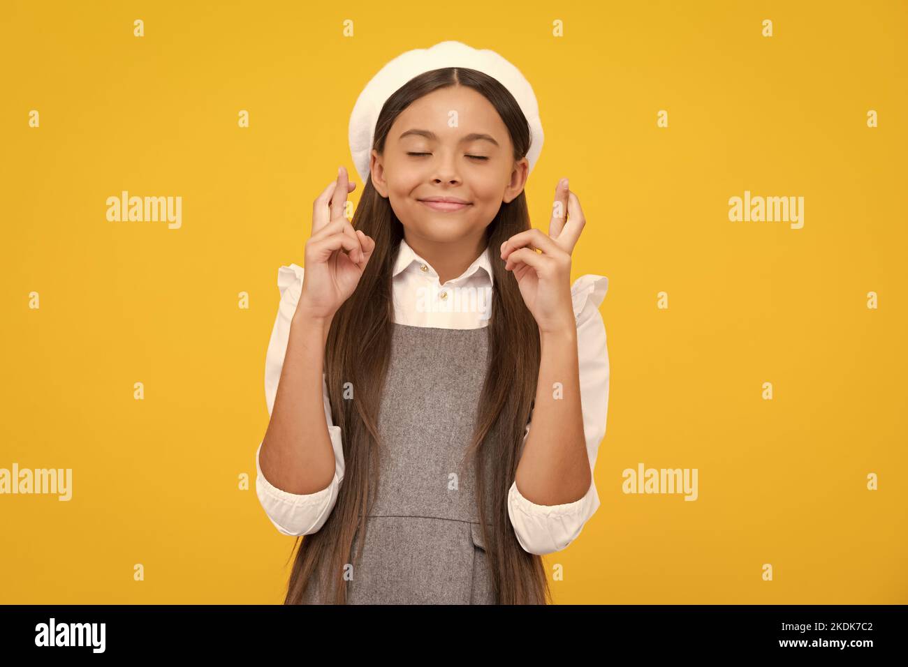 Funny teenager child holding fingers crossed for good luck. Girl prays ...