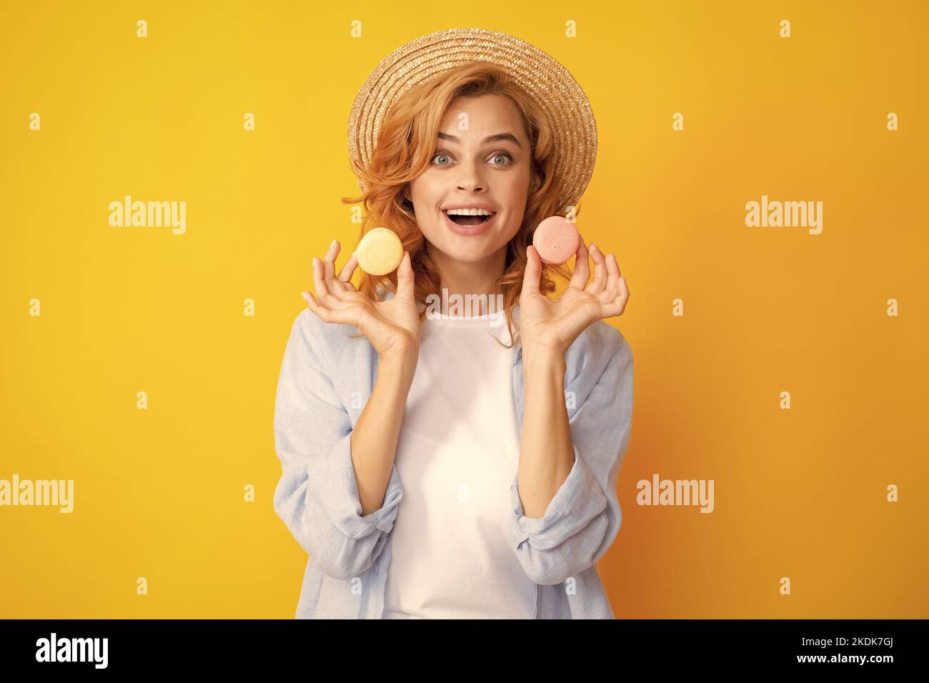 Young pleased woman isolated over yellow background eating macaroons ...
