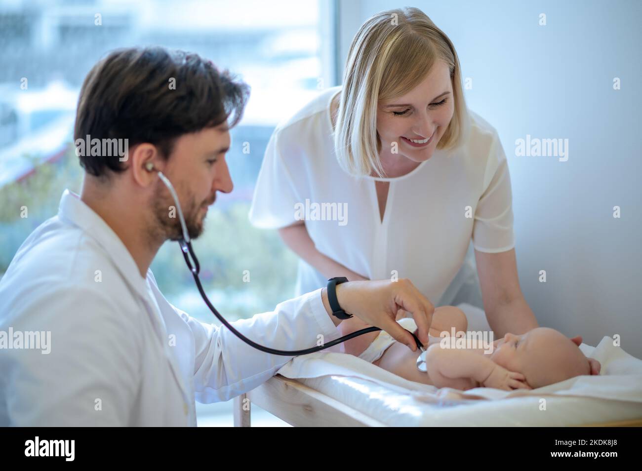 A smiling doctor with a baby and mom hi-res stock photography and ...