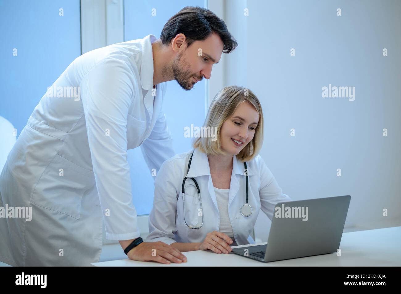Two people in lab coats discussing something and looking interested ...