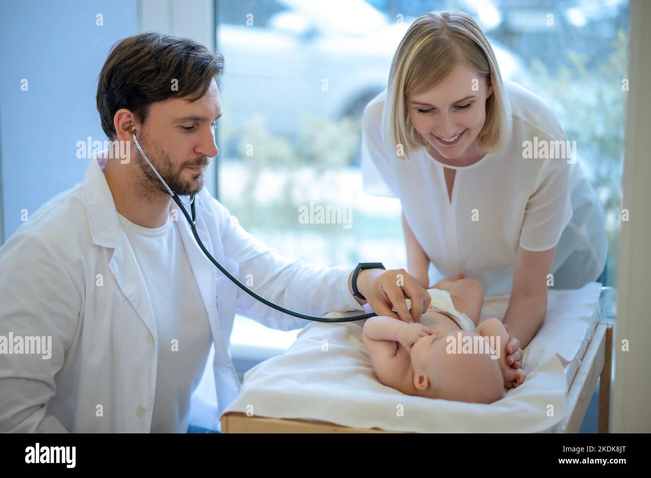 A smiling doctor with a baby and mom hi-res stock photography and ...