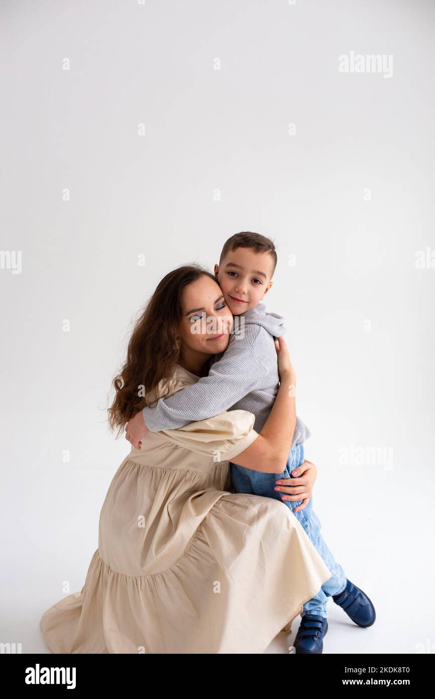Boy preschooler and mother smile and hug on gray background in photo ...
