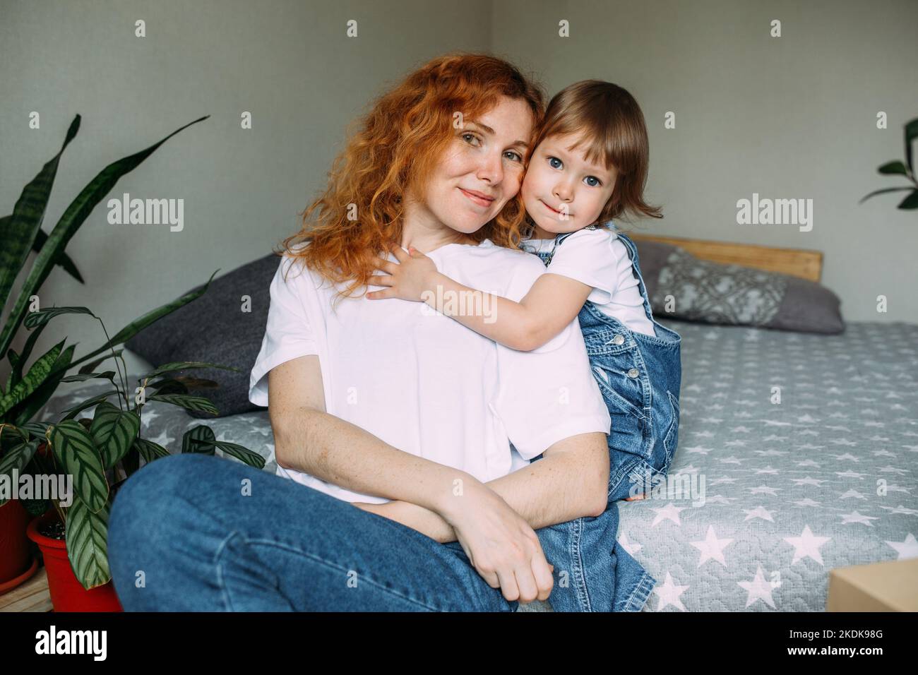 Young mother and child have fun and fool around at home on the bed ...