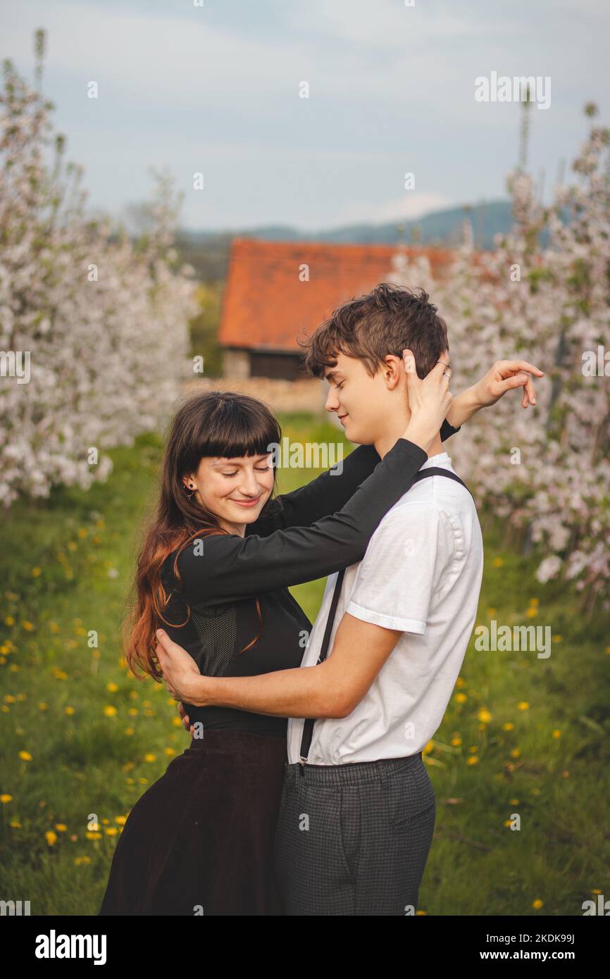 Young strong love between two young people walking under apple trees ...