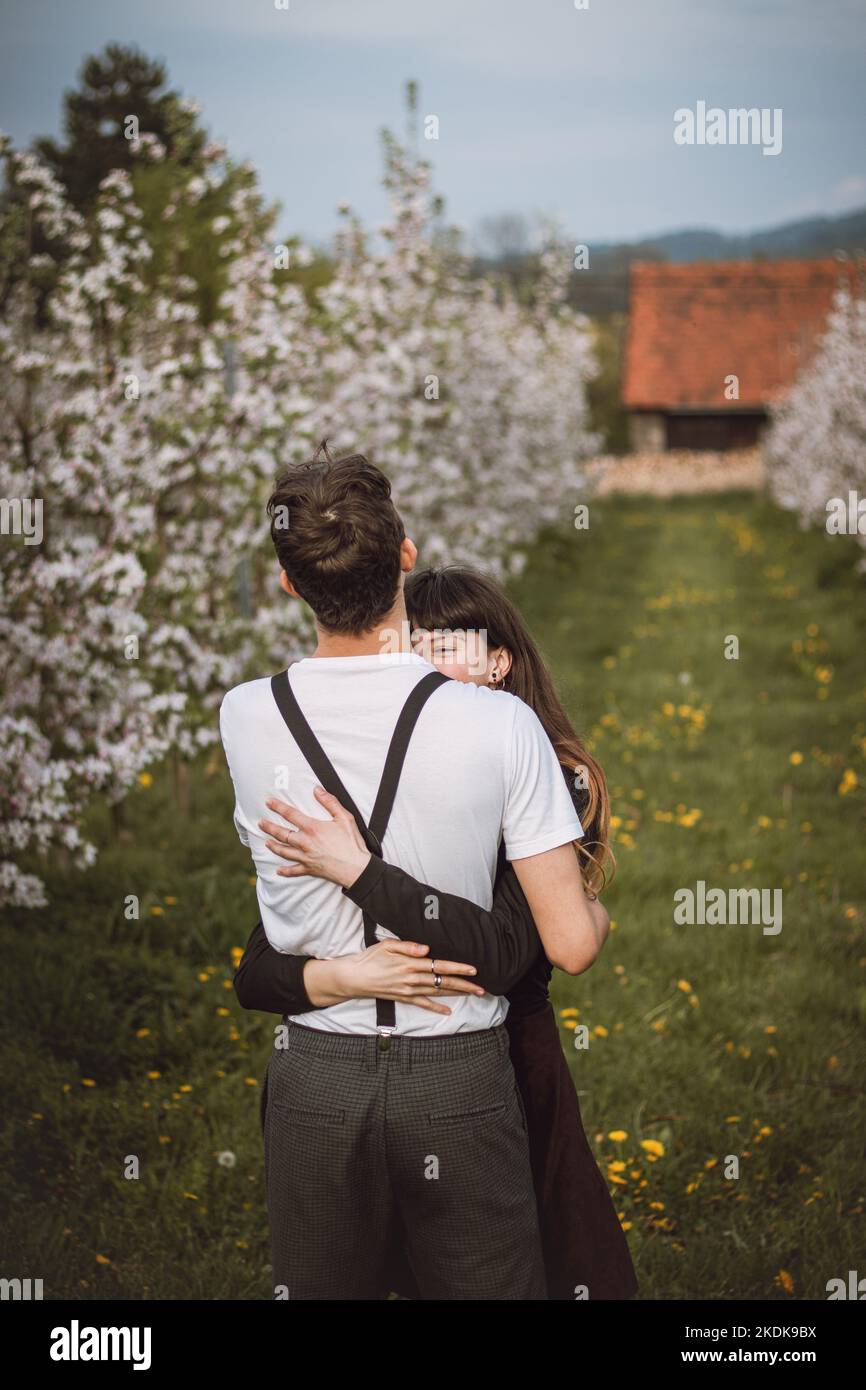 Young strong love between two young people standing under apple trees ...