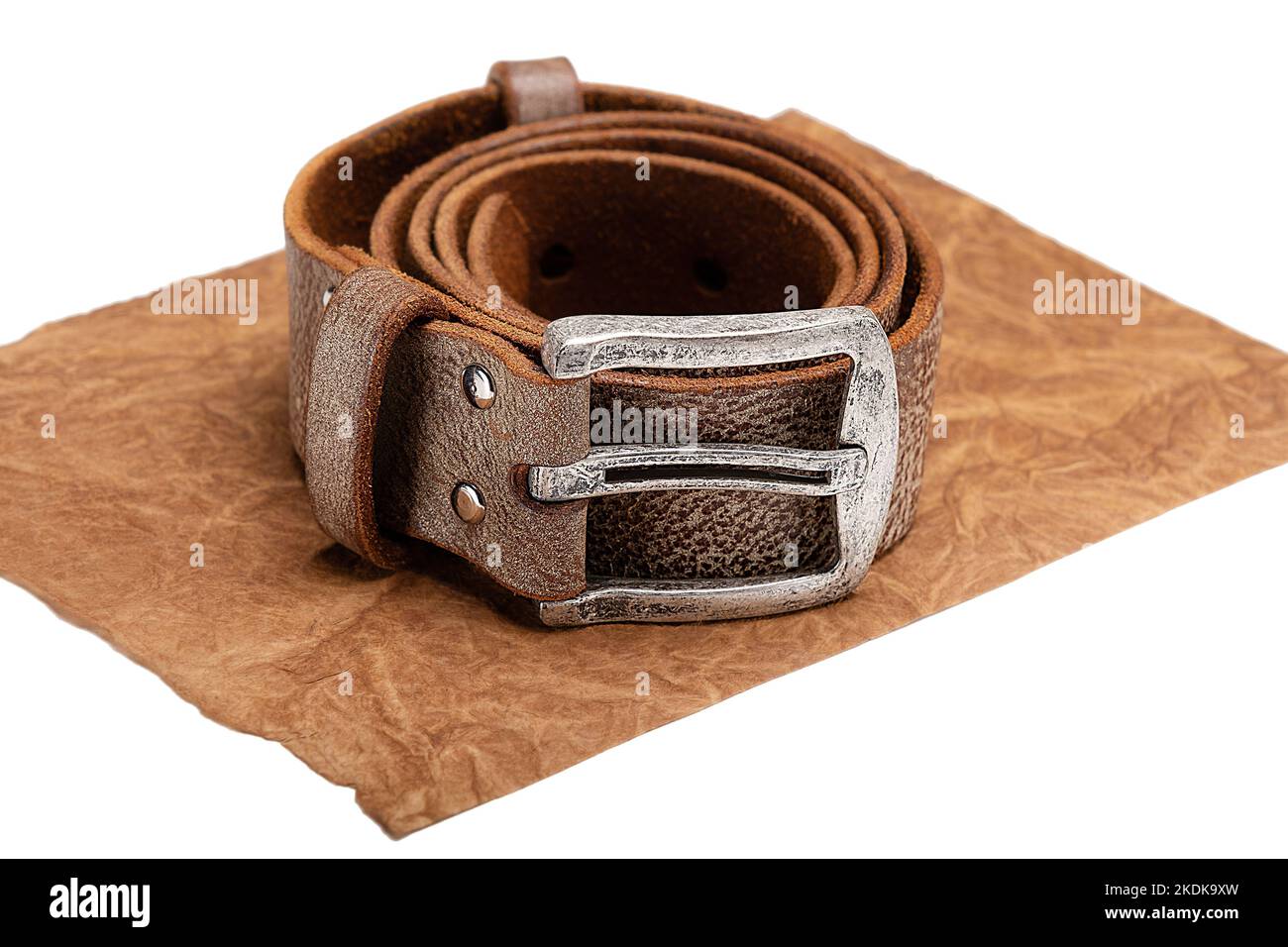 A rolled-up brown leather belt with a metal buckle on a white table ...