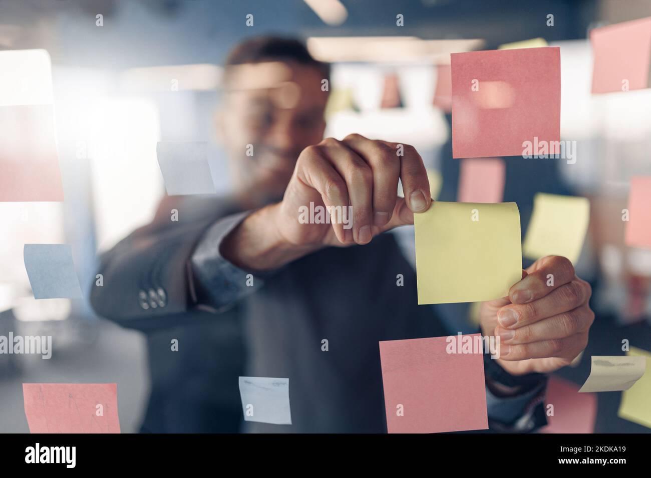Businessman hand's is sticking sticky notes on motivation board in ...