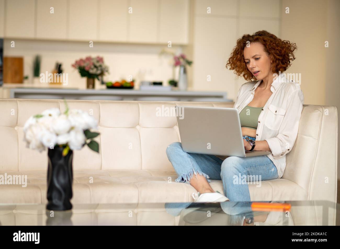 Ginger young woman sitting in the kitchen and working on a laptop Stock ...