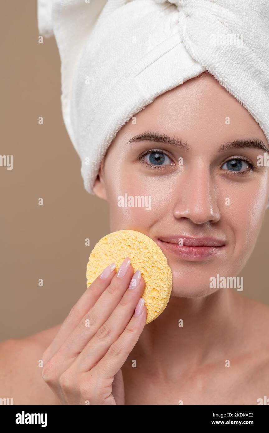 Pretty young girl cleaning her face with a sponge Stock Photo - Alamy