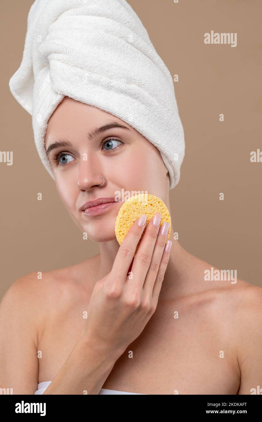 Pretty young girl cleaning her face with a sponge Stock Photo - Alamy