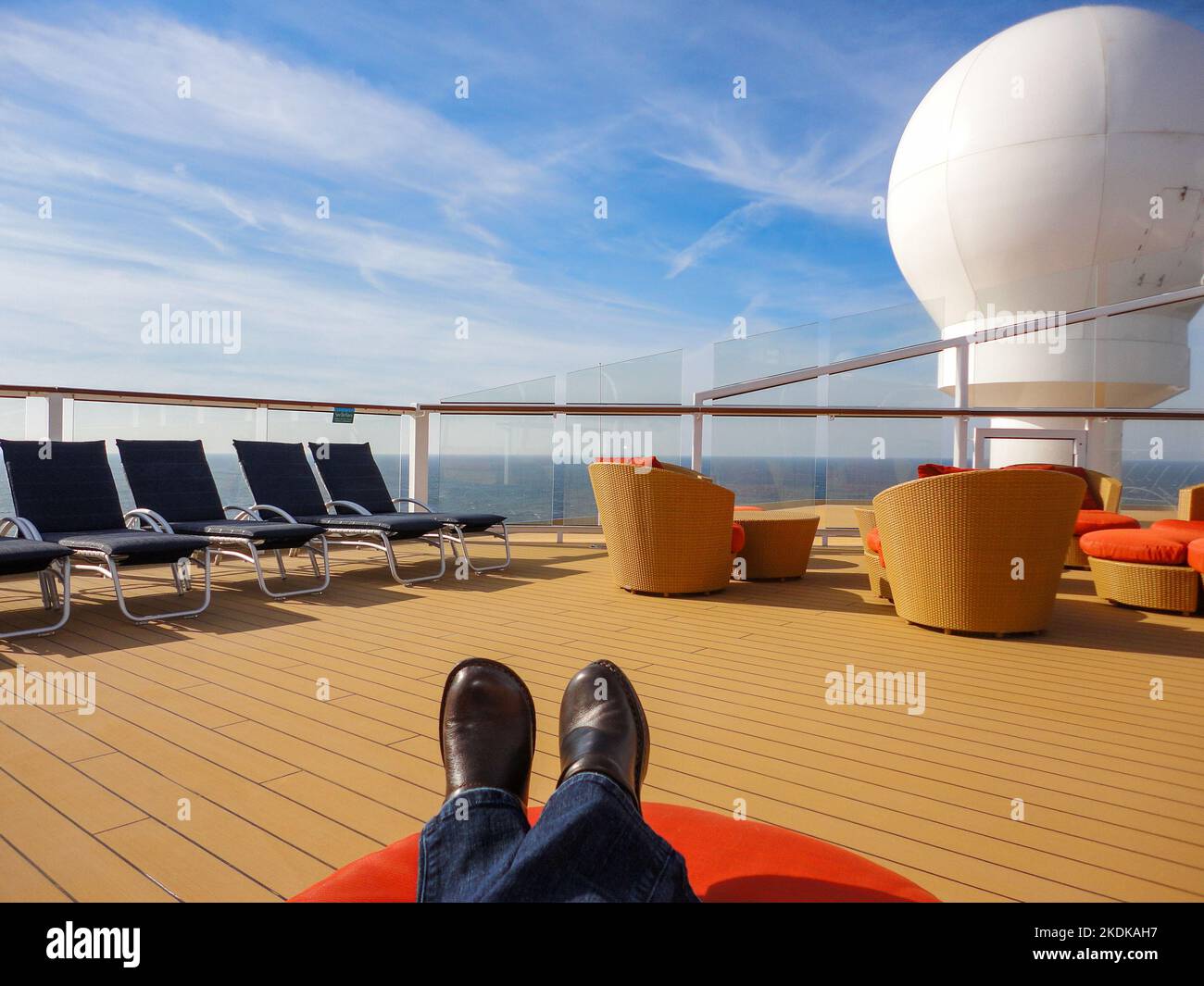 Feet resting on a cushion sitting on the deck of a cruise ship under ...