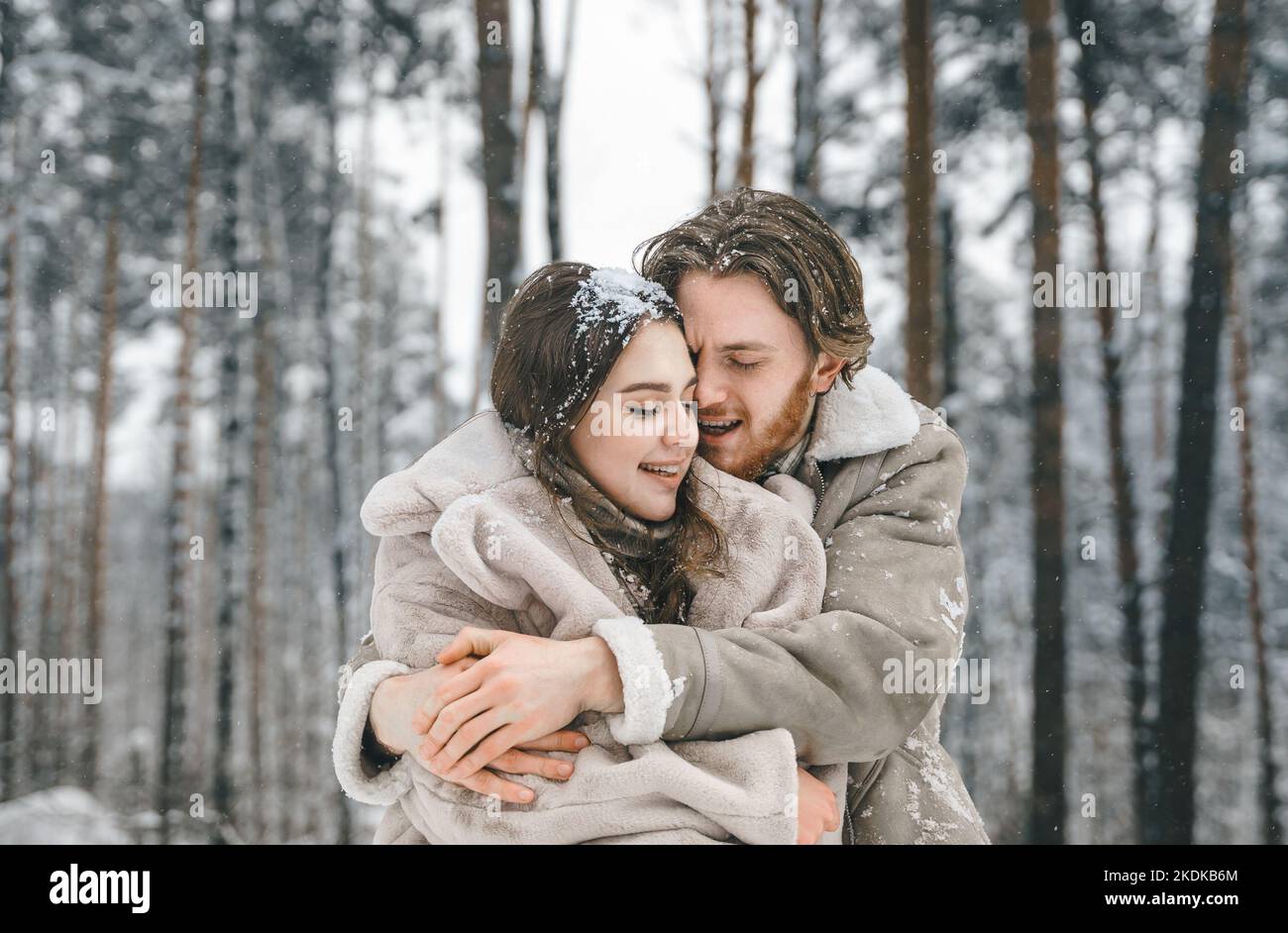 Love romantic young couple. Guy hugging kissing girl in snowy winter ...