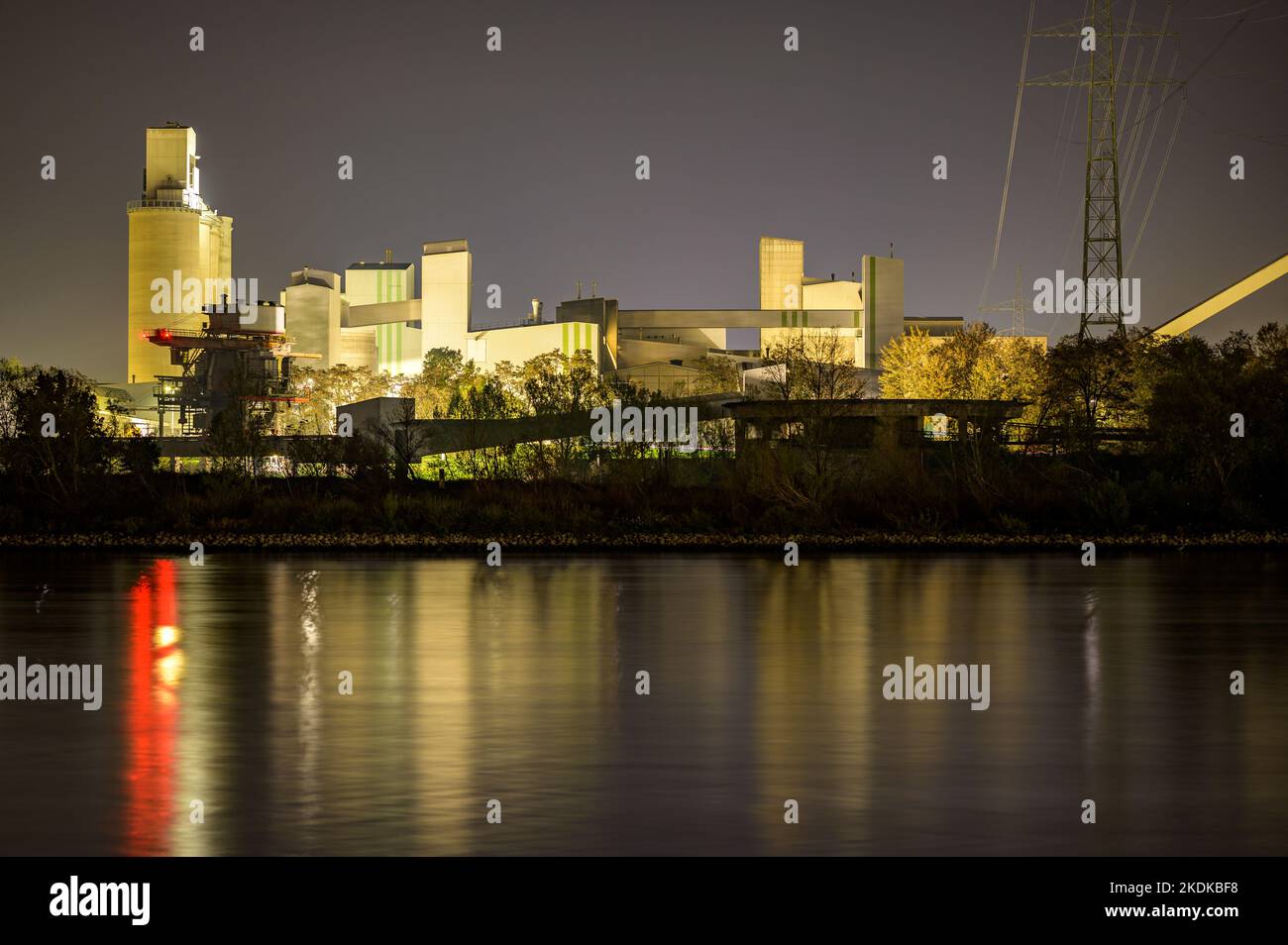 Cement factory on a river bank brightly lit at night Stock Photo - Alamy