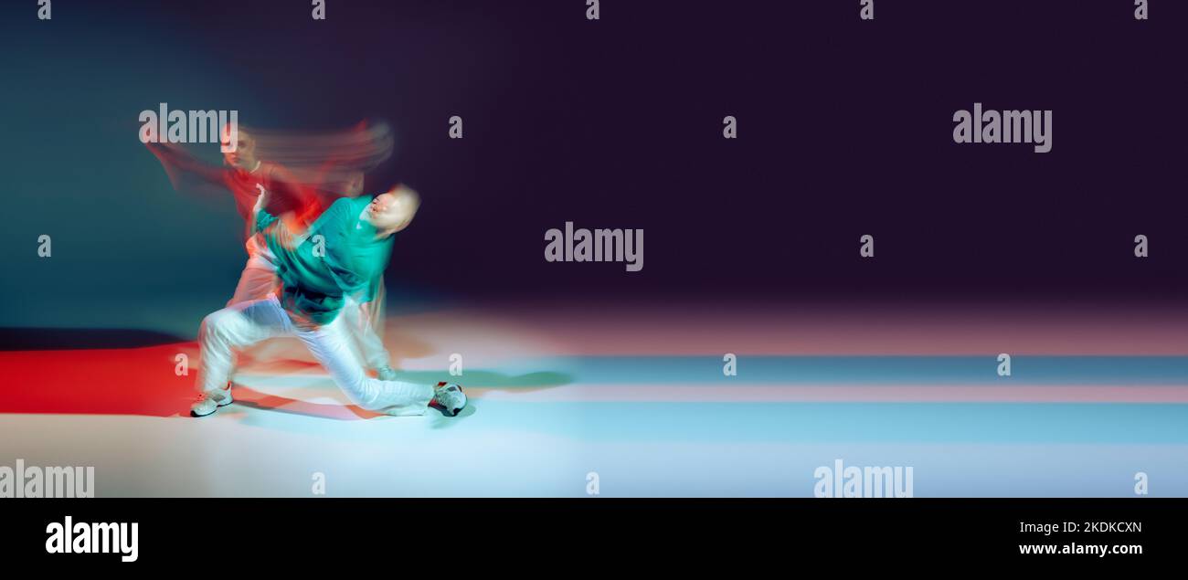 Portrait of young man and woman dancing isolated over green purple ...