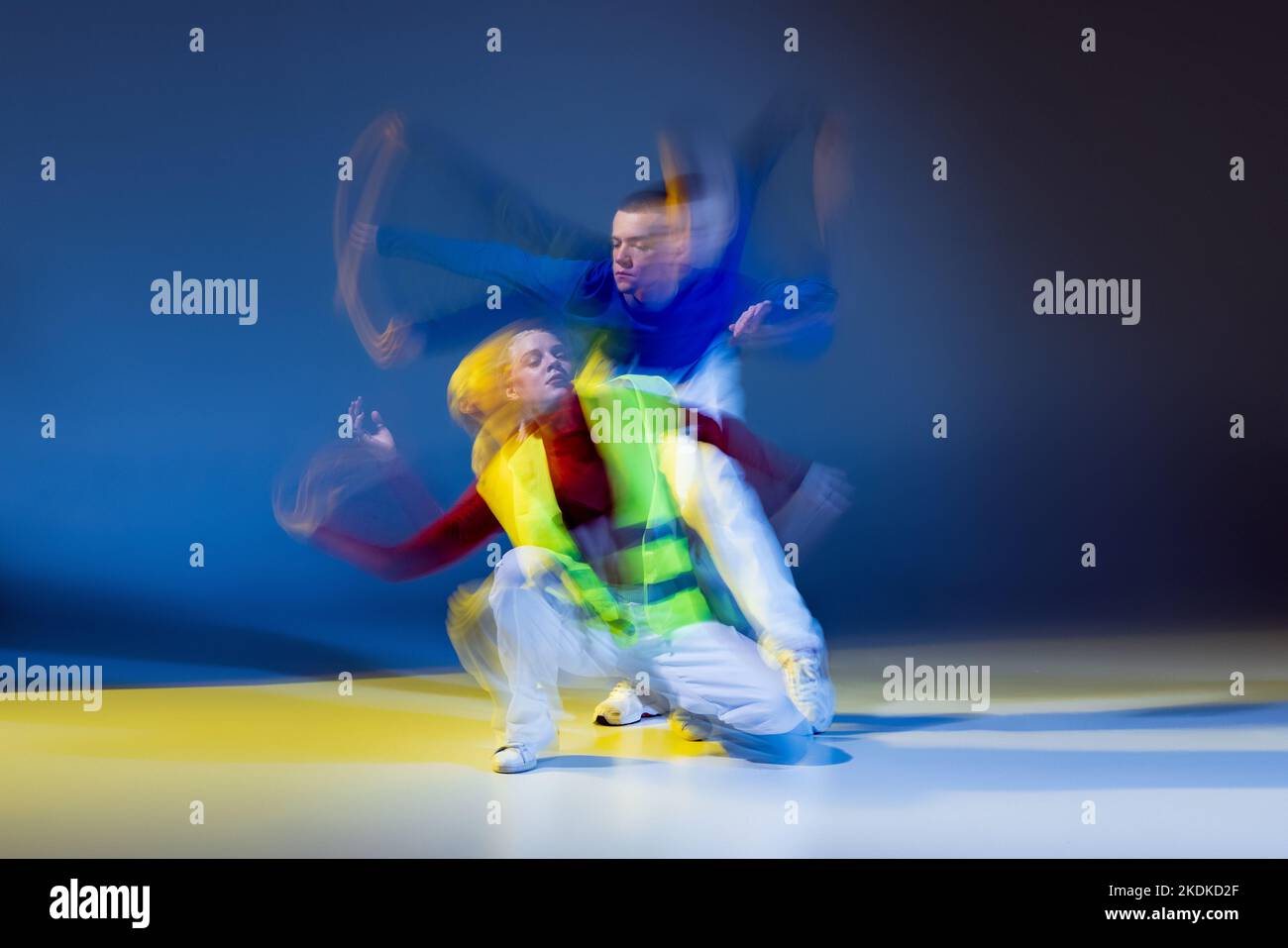 Portrait of young man and woman dancing isolated over blue yellow ...