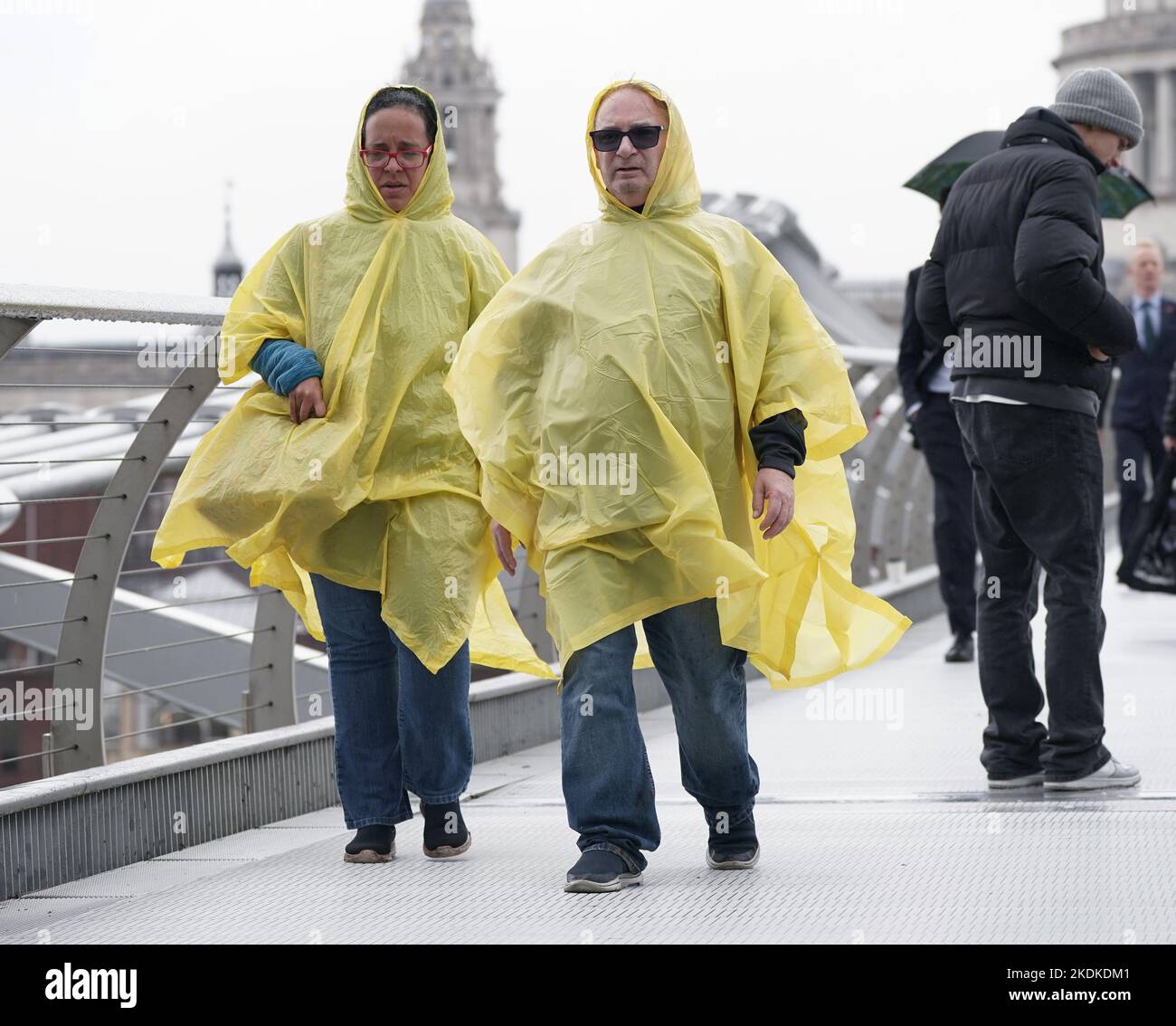 People wearing ponchos during a rain shower, on the Millennium Bridge ...