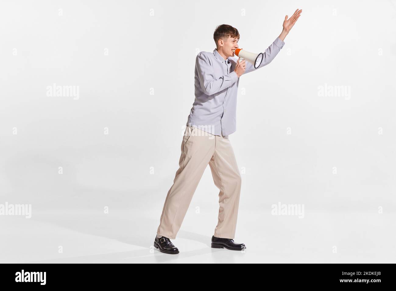 Portrait of young motivated employee shouting in megaphone to raise ...