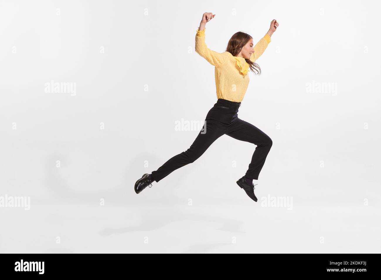 Portrait of young woman jumping, moving forwards isolated over white ...