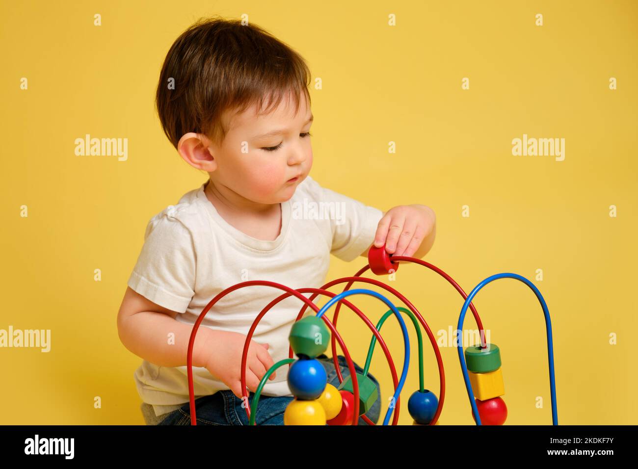 Toddler baby is playing logic educational games on a studio yellow ...