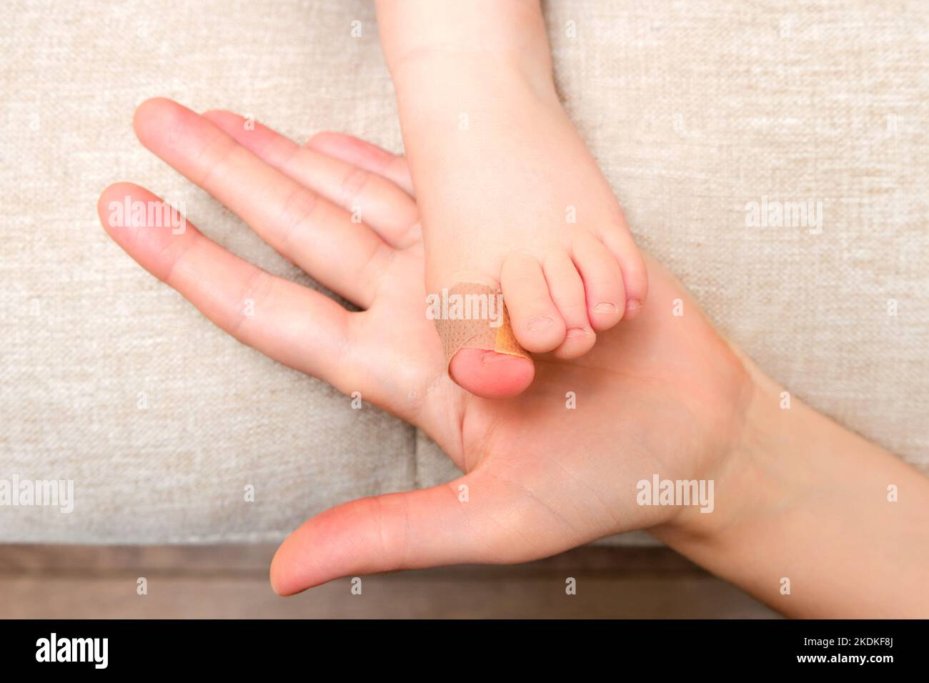 Mother woman sticks a medical adhesive plaster on the toddler baby leg ...