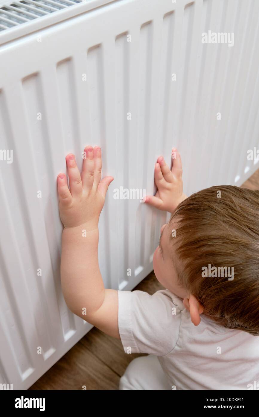 Toddler baby holding on to the radiator, child hand on the heating ...