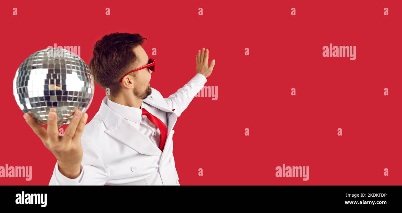 Happy man holding disco ball and dancing isolated on red copy space ...