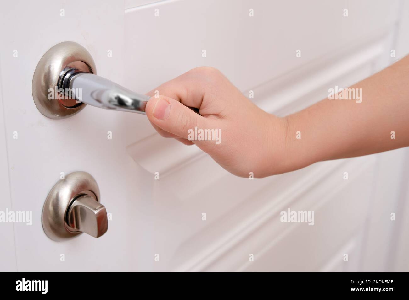 A woman opens the door holding the handle, hand close-up. White wooden ...