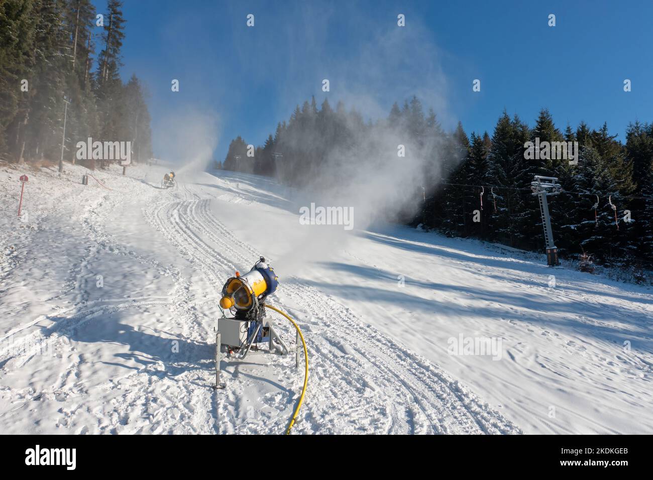 Snow cannon in winter mountains slope. Snow-gun spraying artificial ice ...