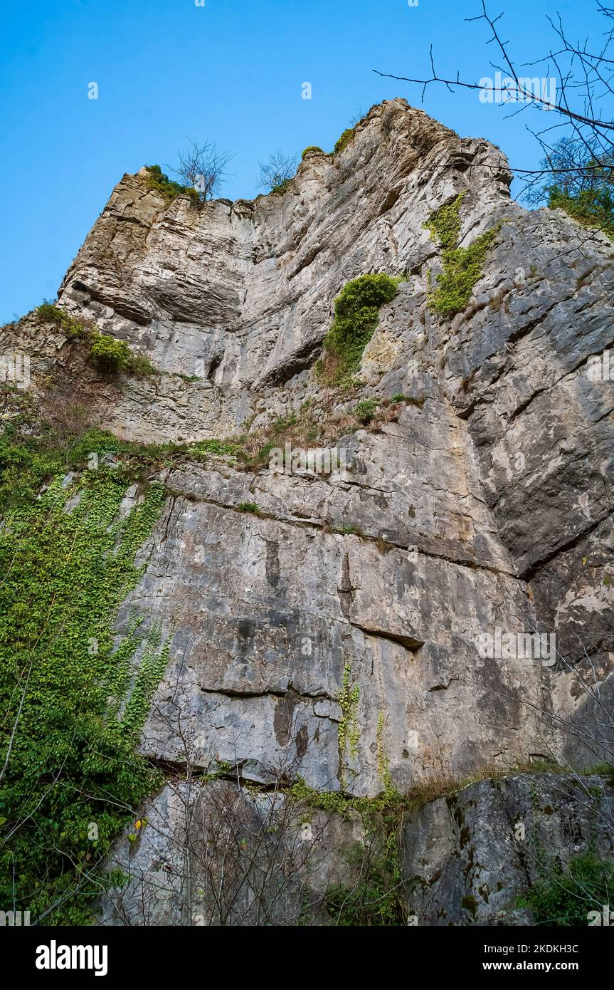 Tall limestone cliffs, partly quarried, with cave entrances and man ...