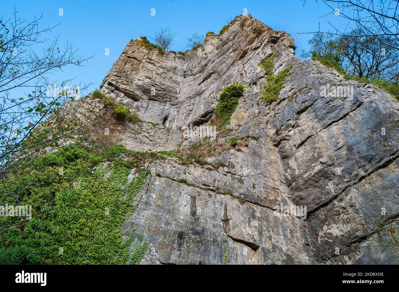 Tall limestone cliffs, partly quarried, with cave entrances and man ...