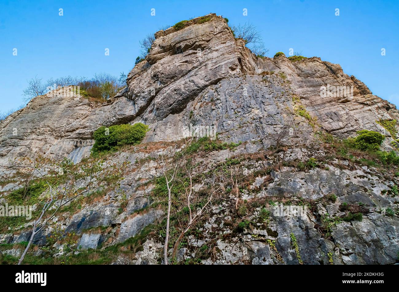 Tall limestone cliffs, partly quarried, with cave entrances and man ...