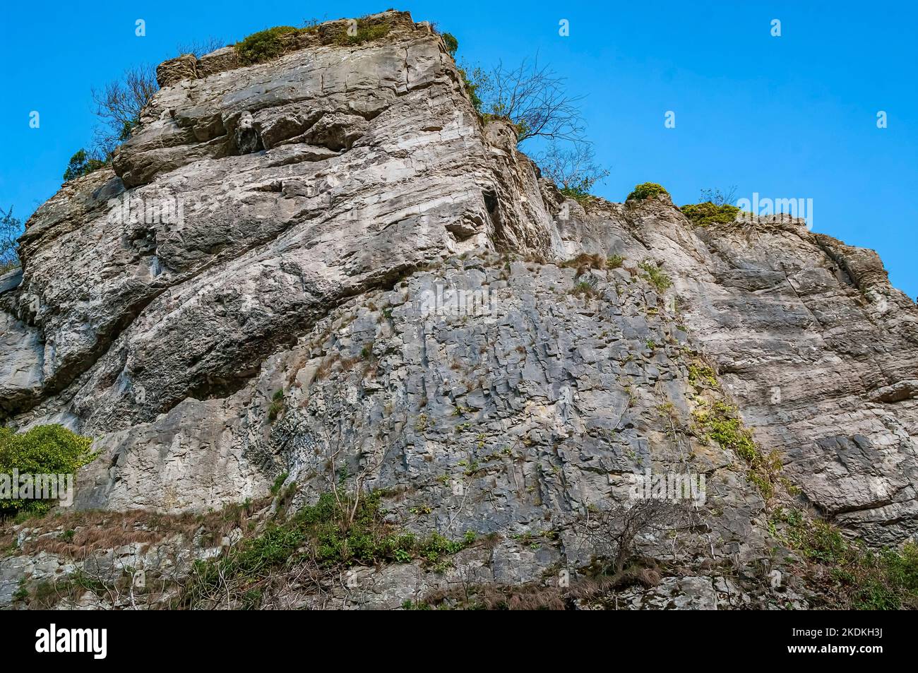 Tall limestone cliffs, partly quarried, with cave entrances and man ...