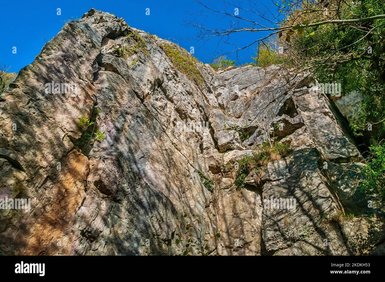 Tall limestone cliffs, partly quarried, with cave entrances and man ...