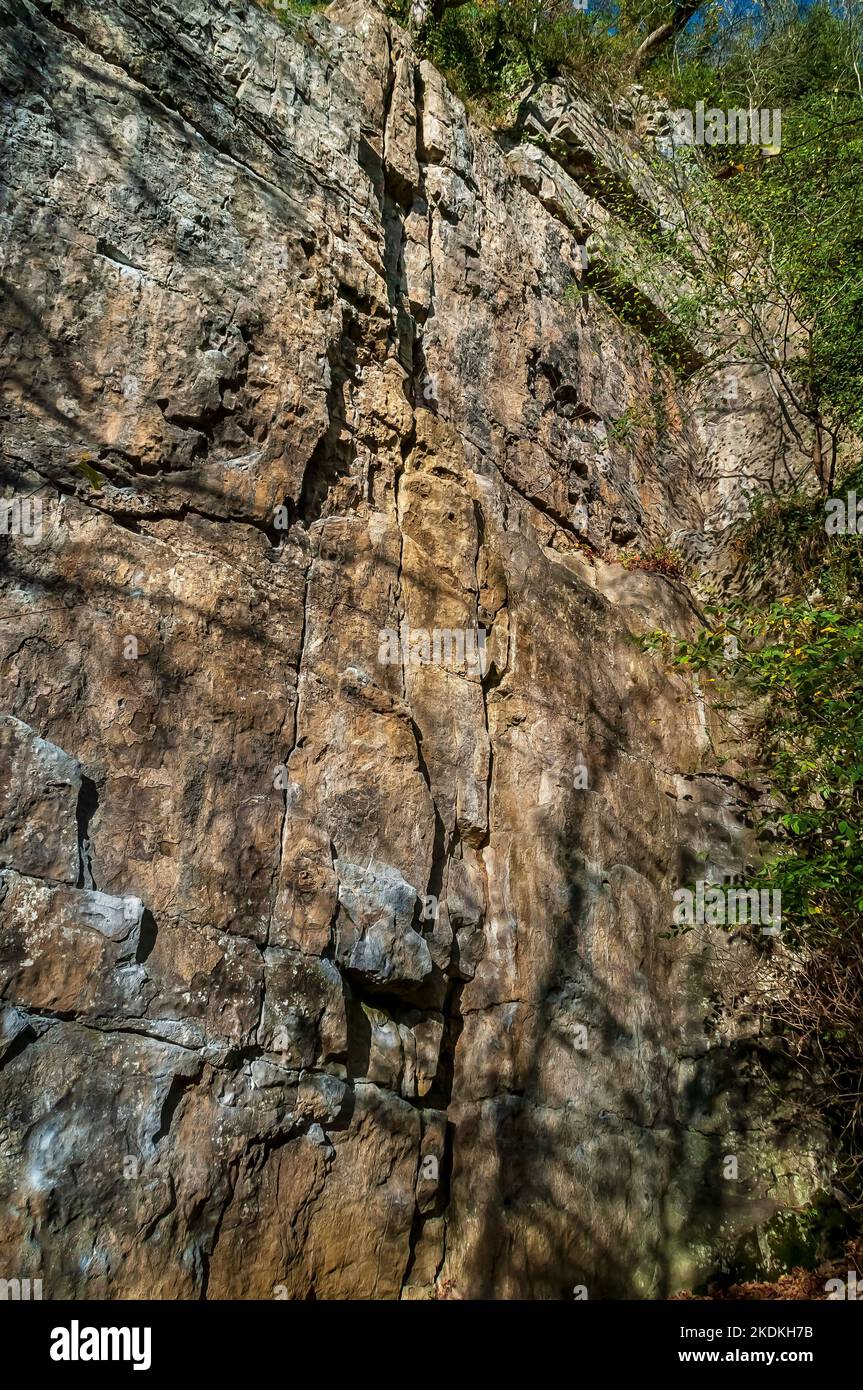Tall limestone cliffs, partly quarried, with cave entrances and man ...