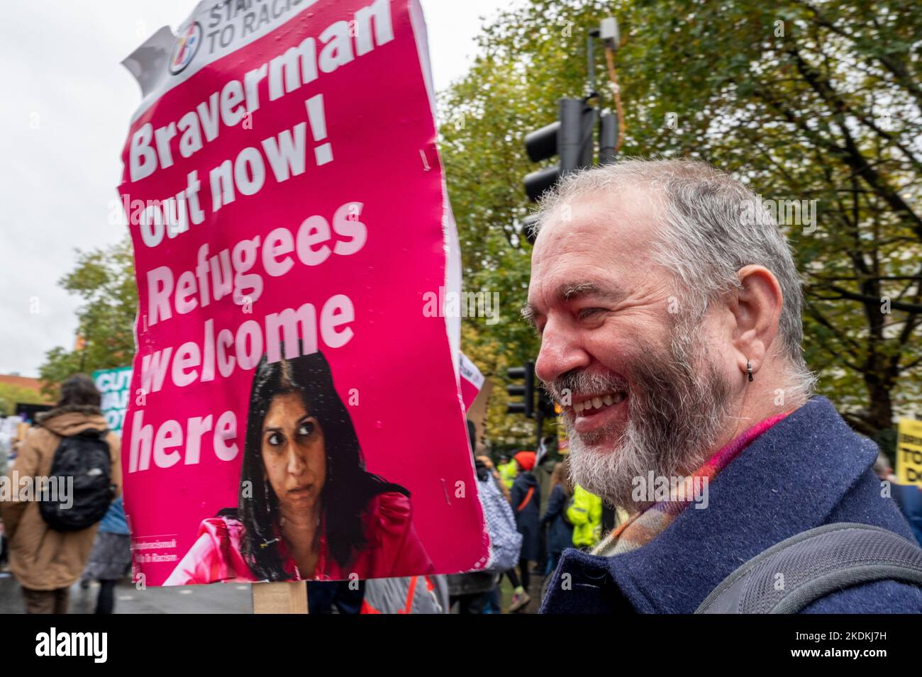 A Smiling Man Carrying A Poster Braverman Out Now Refugees Welcome Here During A