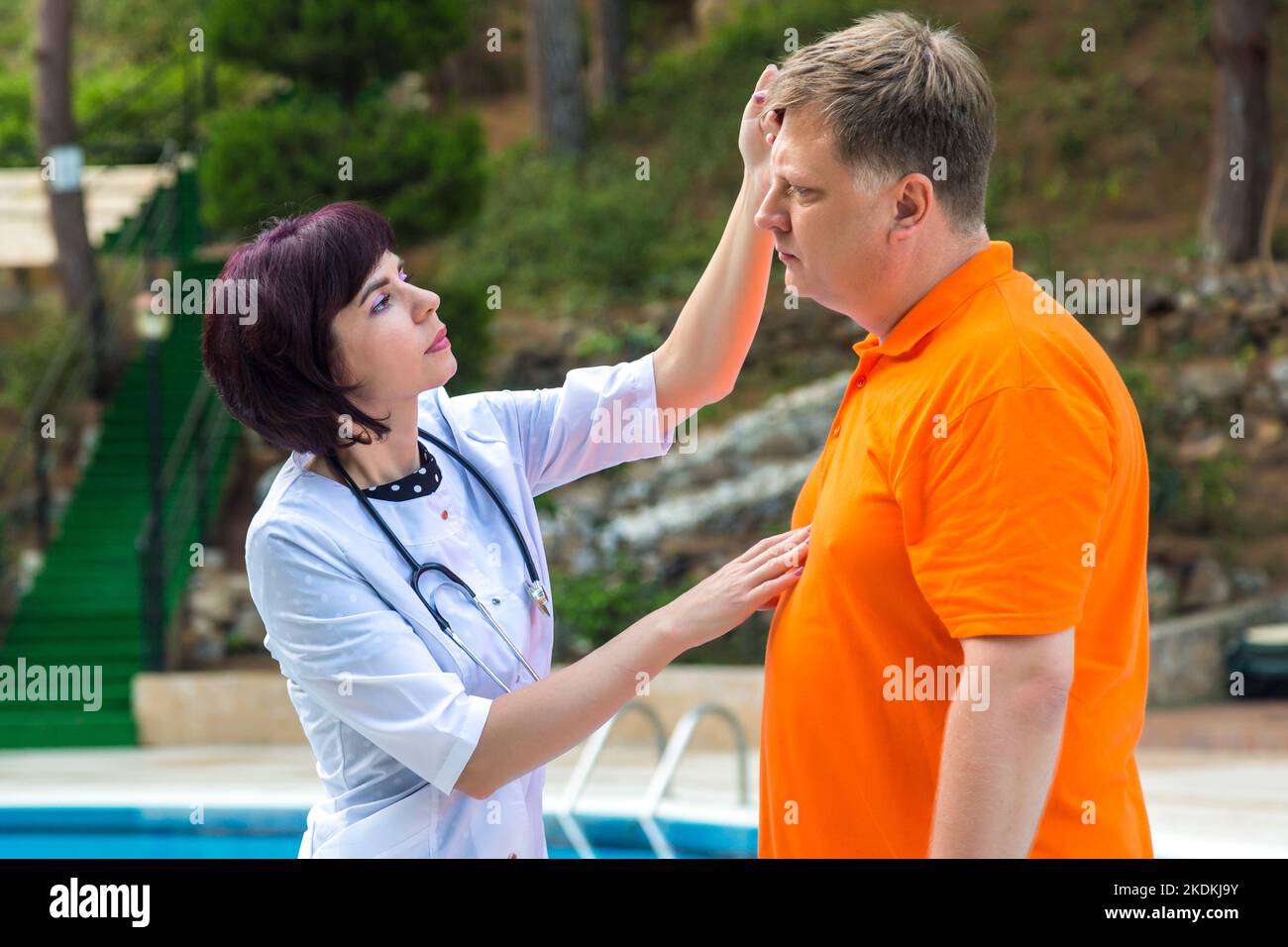 Woman doctor touching forehead of sick man on the street Stock Photo ...