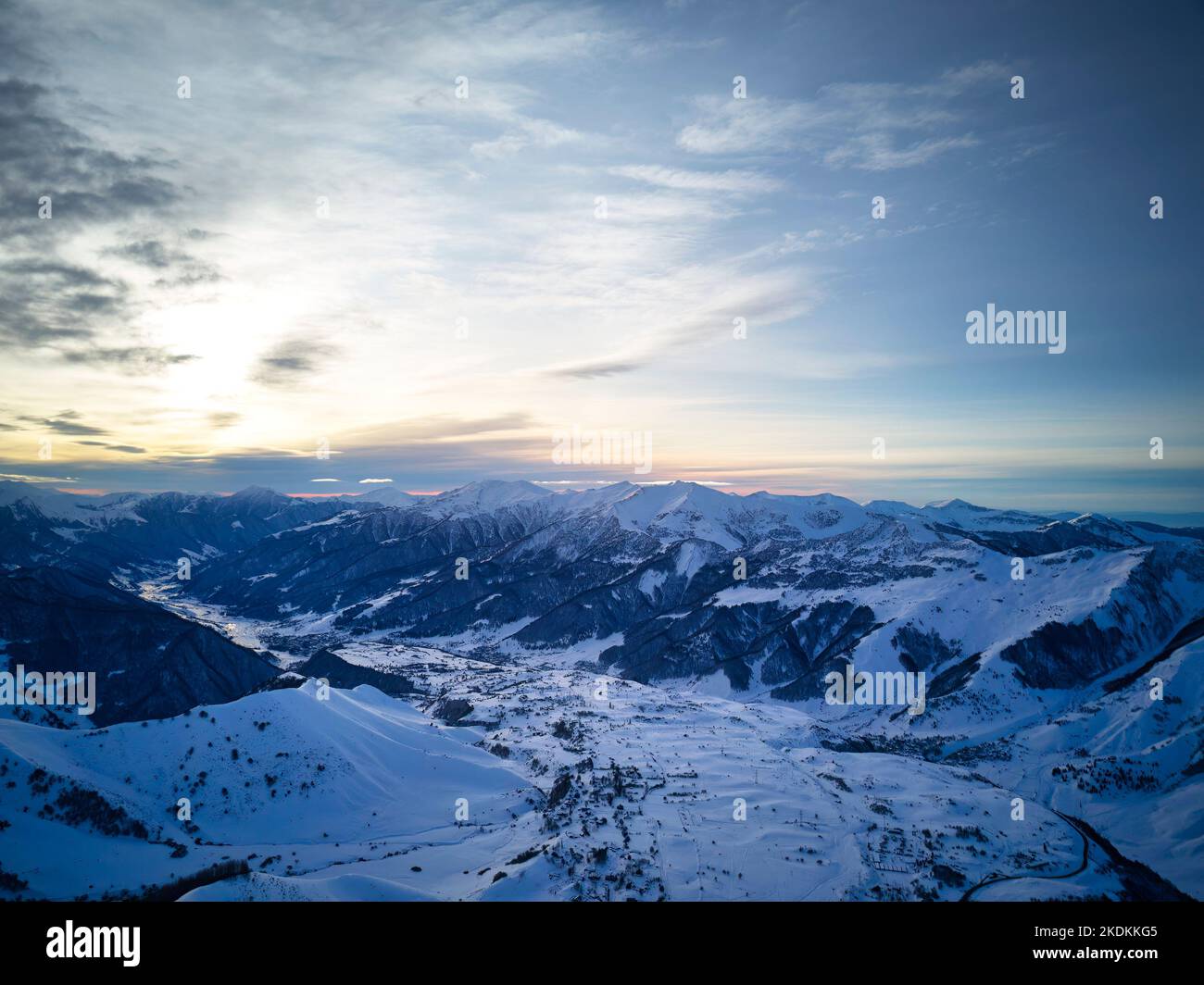 Wide aerial panorama of snowy mountain ridge at ski resort village on ...