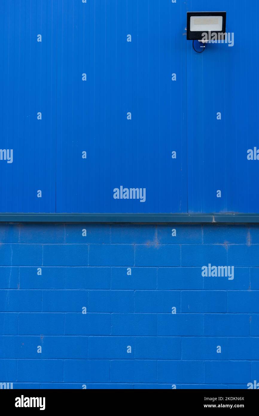 Led spotlight on warehouse facade painted in intense blue of mixed ...