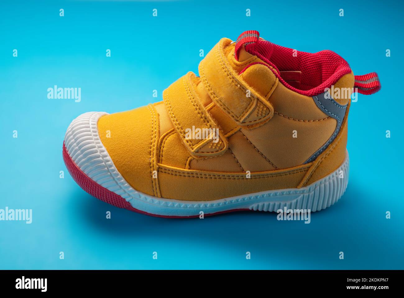 Yellow baby shoes. Kids sport sneakers isolated on blue background ...