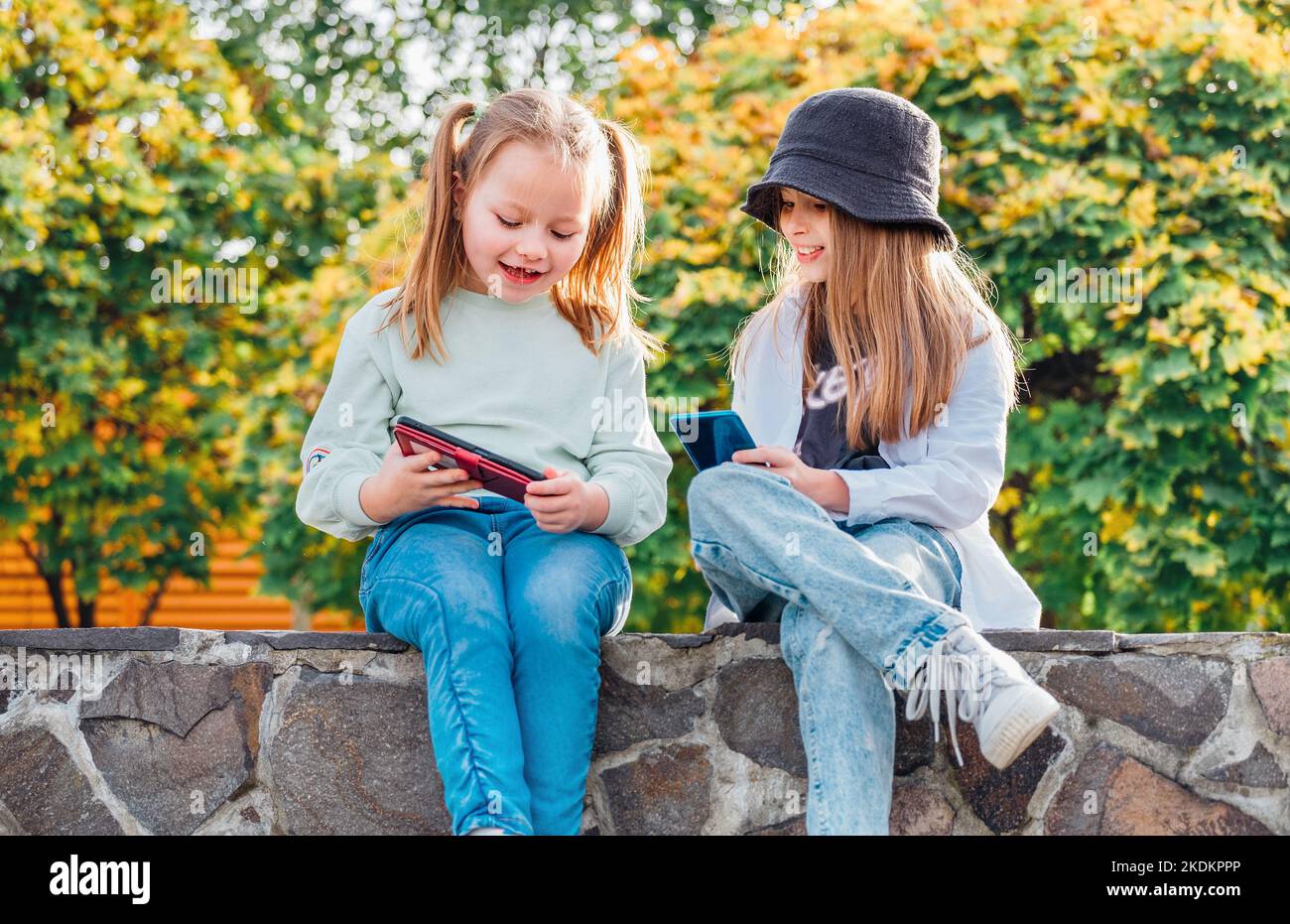 Two smiling little sister girls kids sitting and browsing their ...