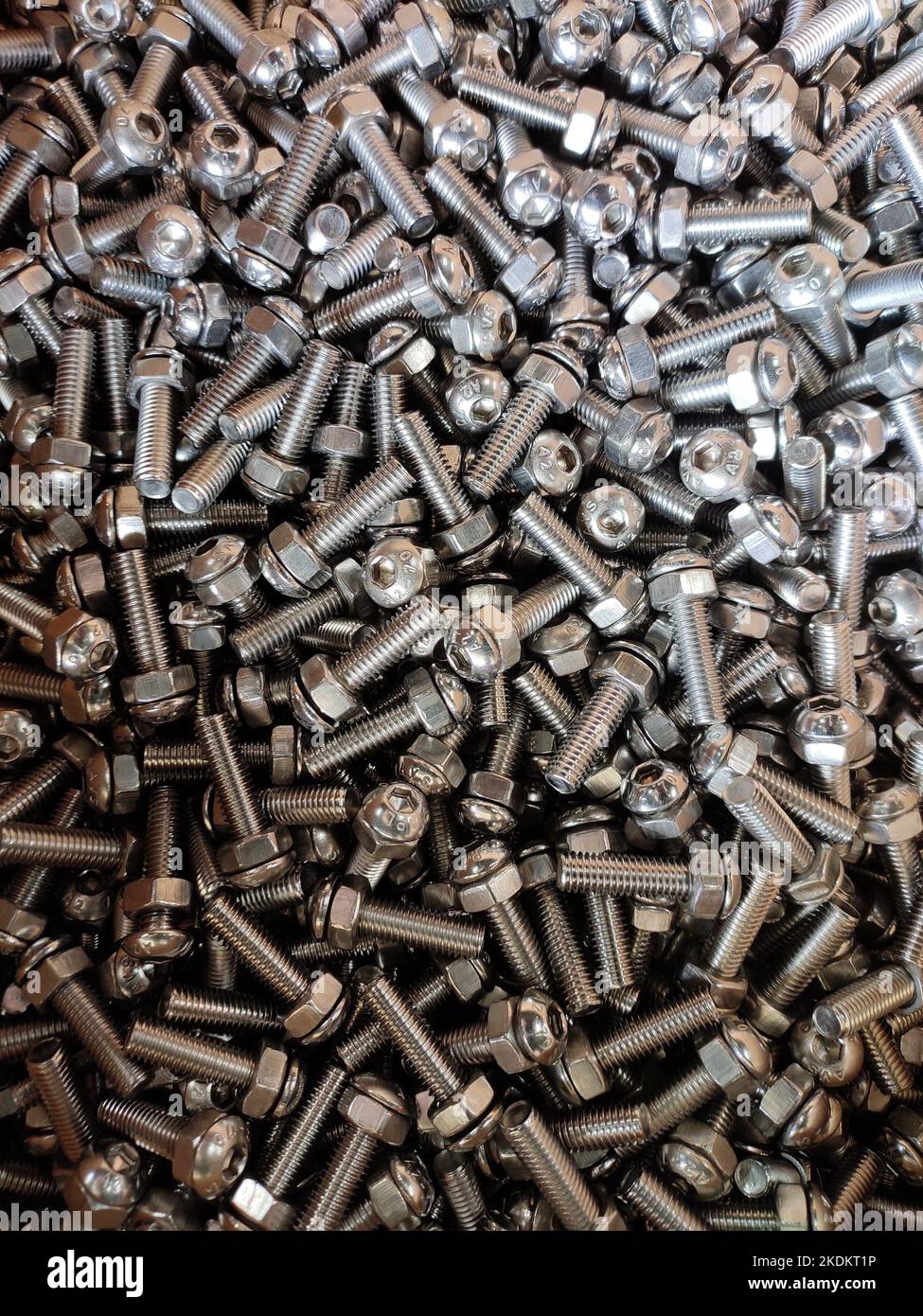 A close-up of stainless steel hex bolts and nuts in a shiny pile ...